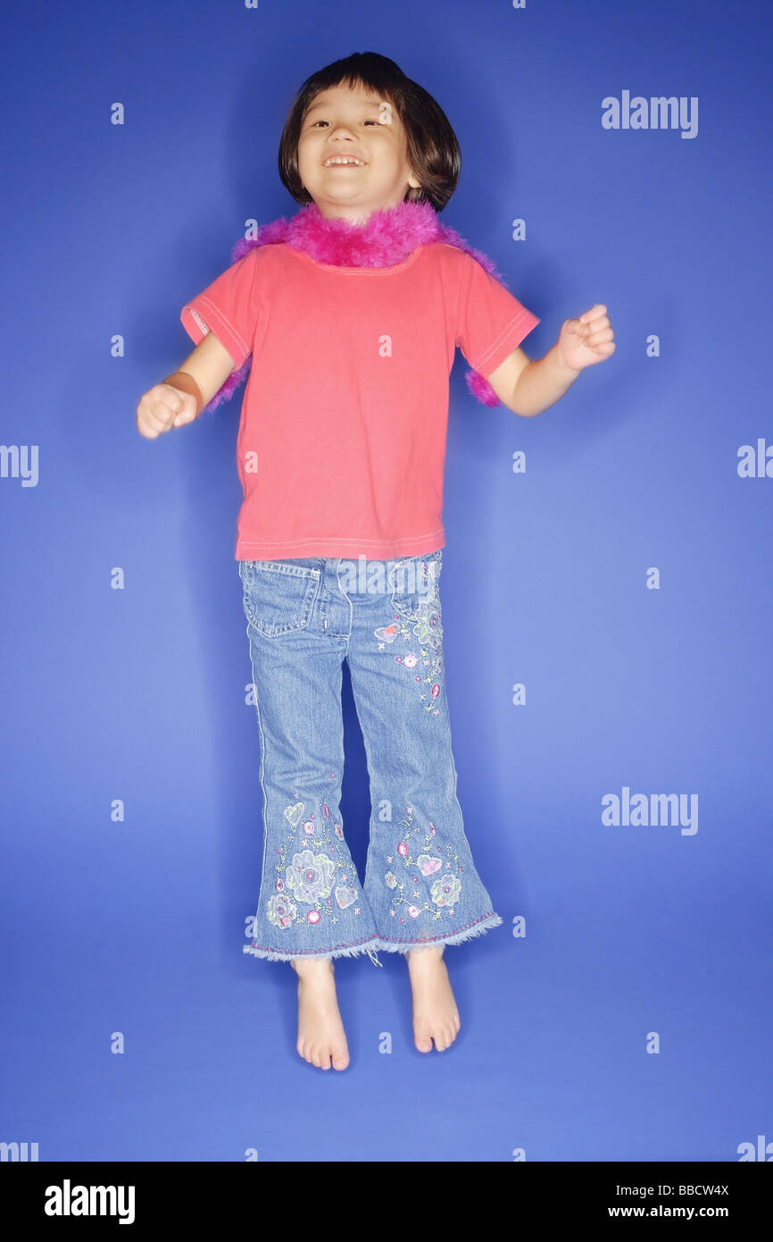 Young girl jumping, blue background Stock Photo - Alamy