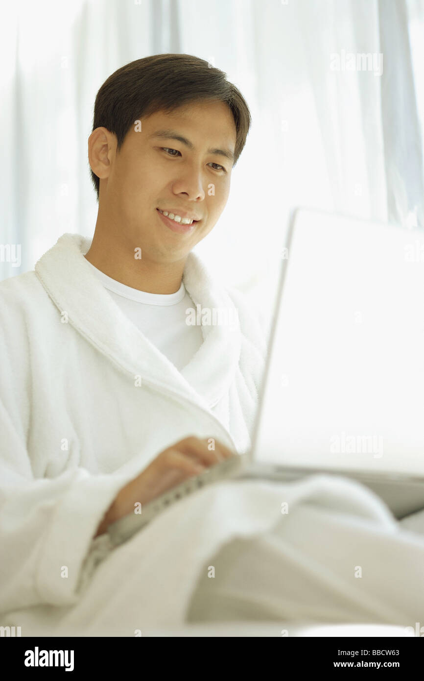 Young man wearing robe, using laptop Stock Photo - Alamy