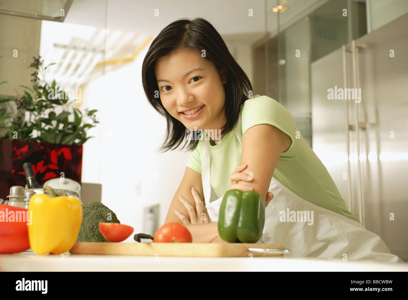 Young woman leaning on kitchen counter, looking at camera Stock Photo ...