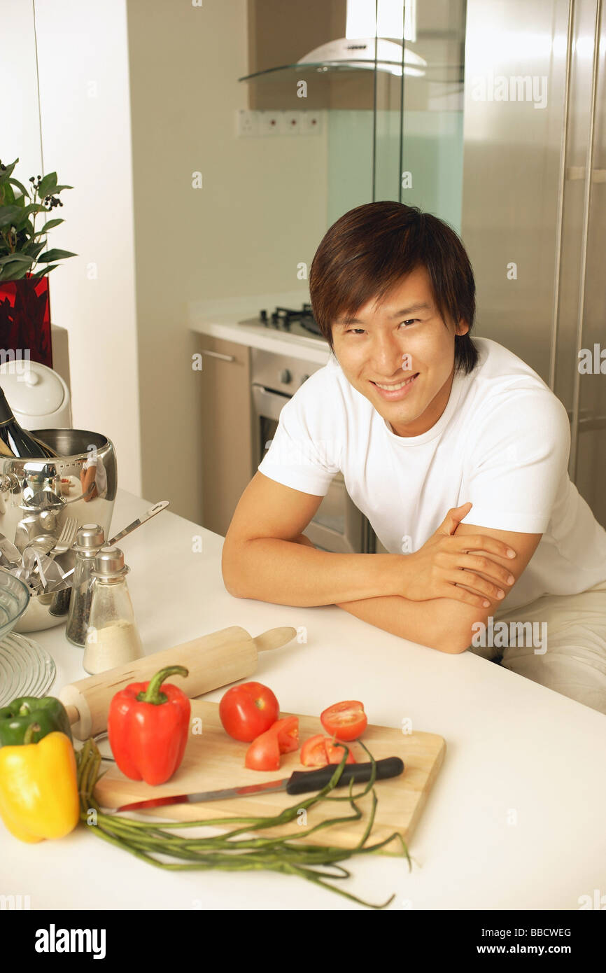 Young man leaning on kitchen counter, looking at camera Stock Photo - Alamy