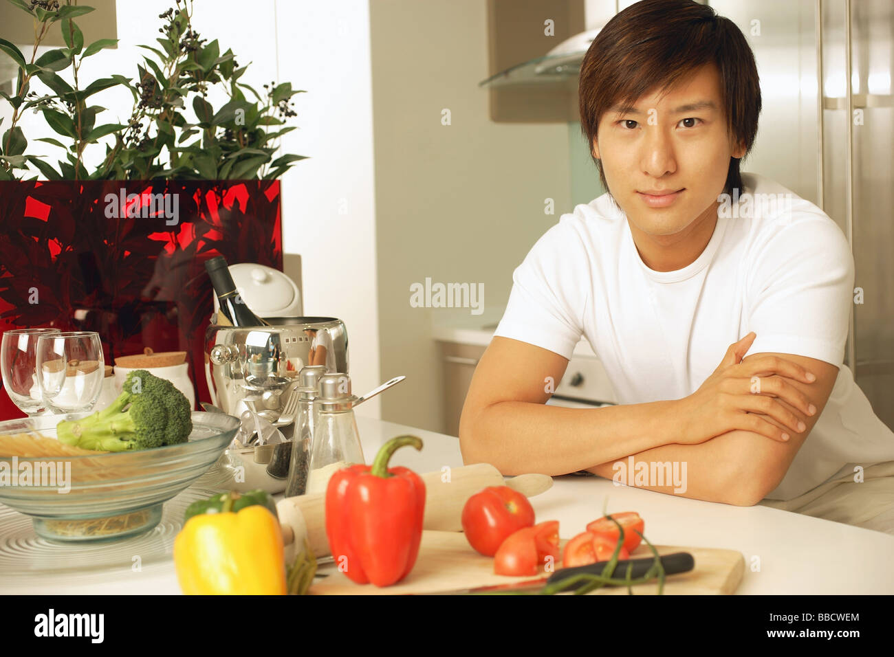 Young man leaning on kitchen counter, arms crossed Stock Photo - Alamy