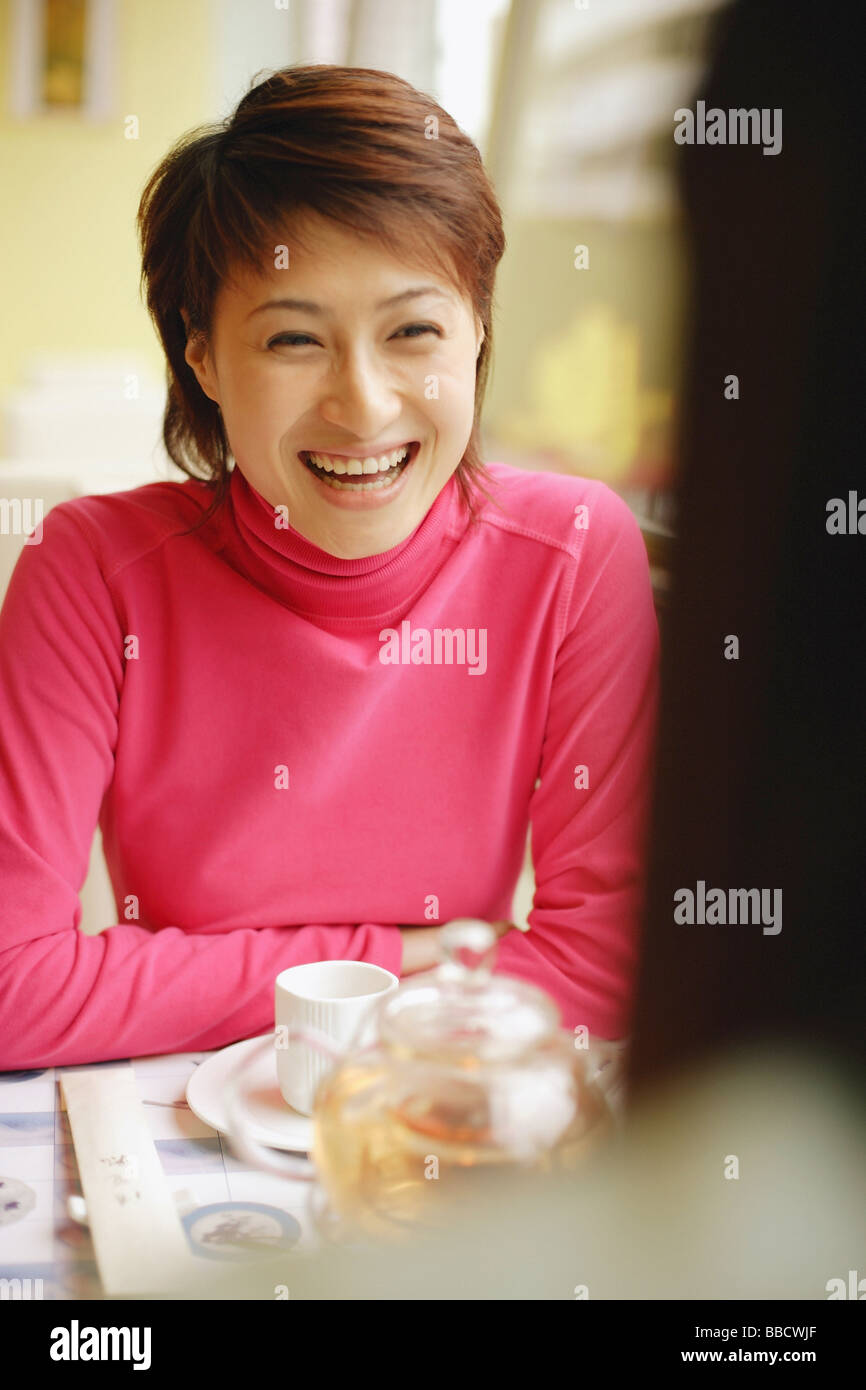 Young woman sitting opposite another person, smiling, arms crossed ...
