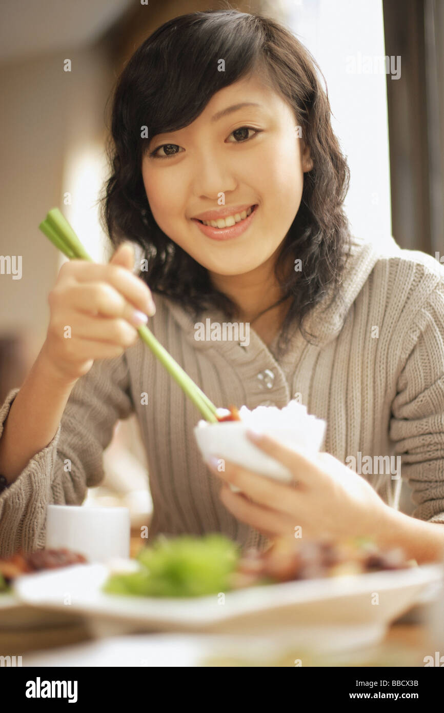 Young woman eating at a restaurant, looking at camera Stock Photo - Alamy