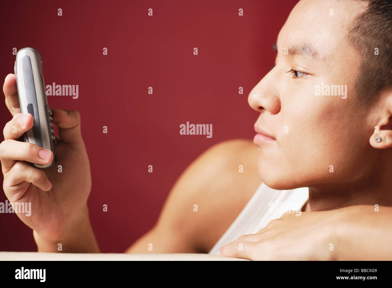Young man holding mobile phone, sideview Stock Photo - Alamy