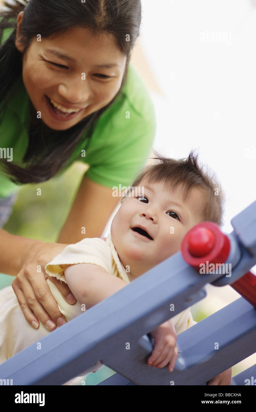 Mother supporting baby girl, baby girl holding ladder Stock Photo - Alamy