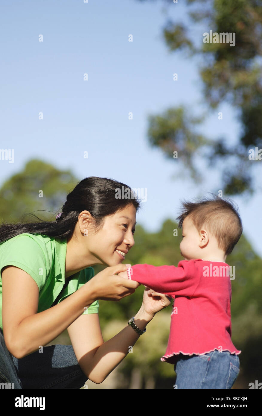 Baby girl standing, mother holding her up Stock Photo - Alamy