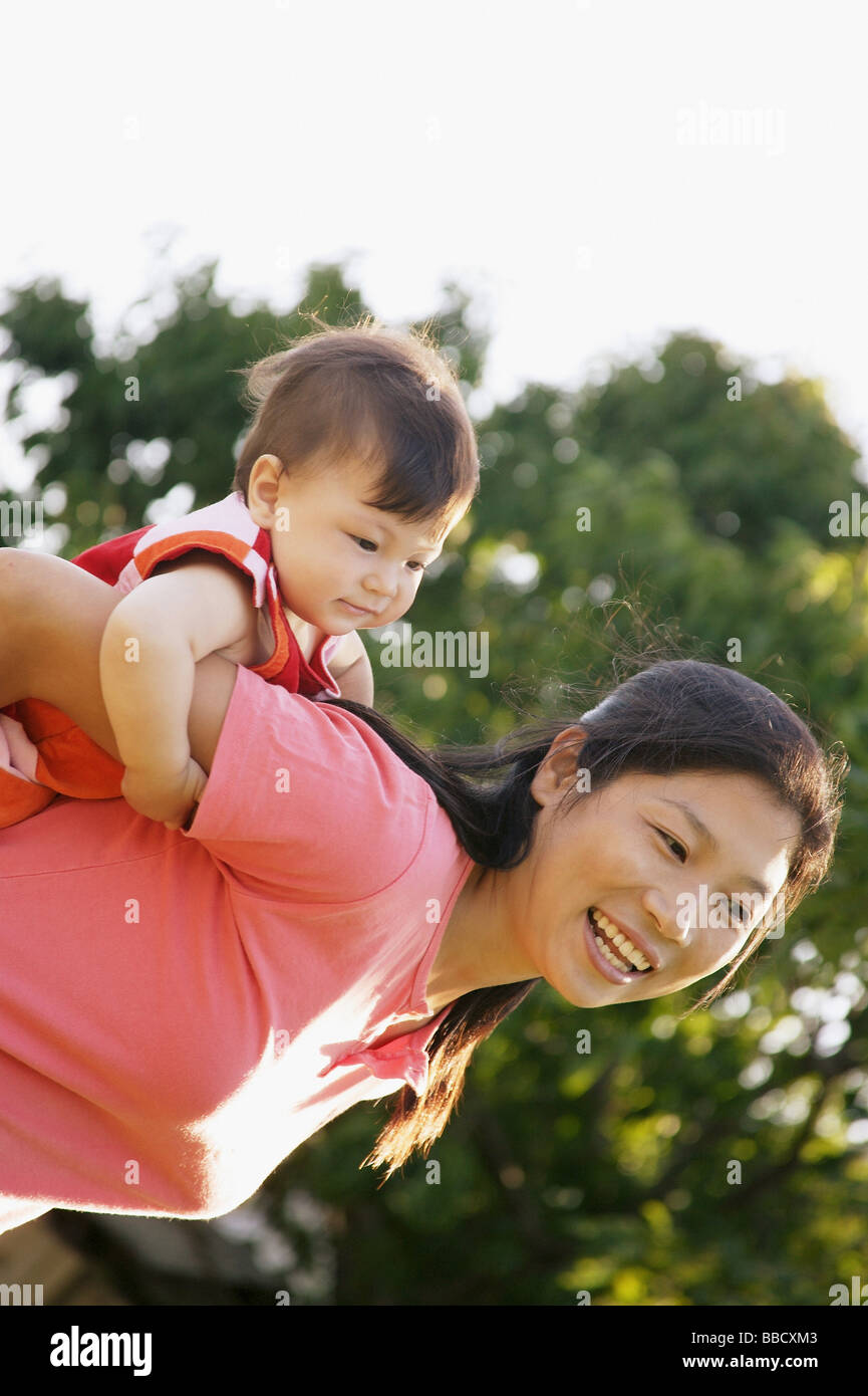 Mother carrying baby girl on her back Stock Photo - Alamy