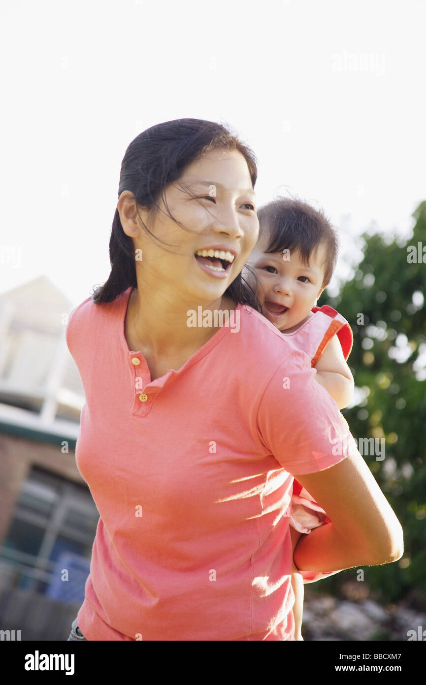 Mother carrying baby girl on her back, laughing Stock Photo - Alamy