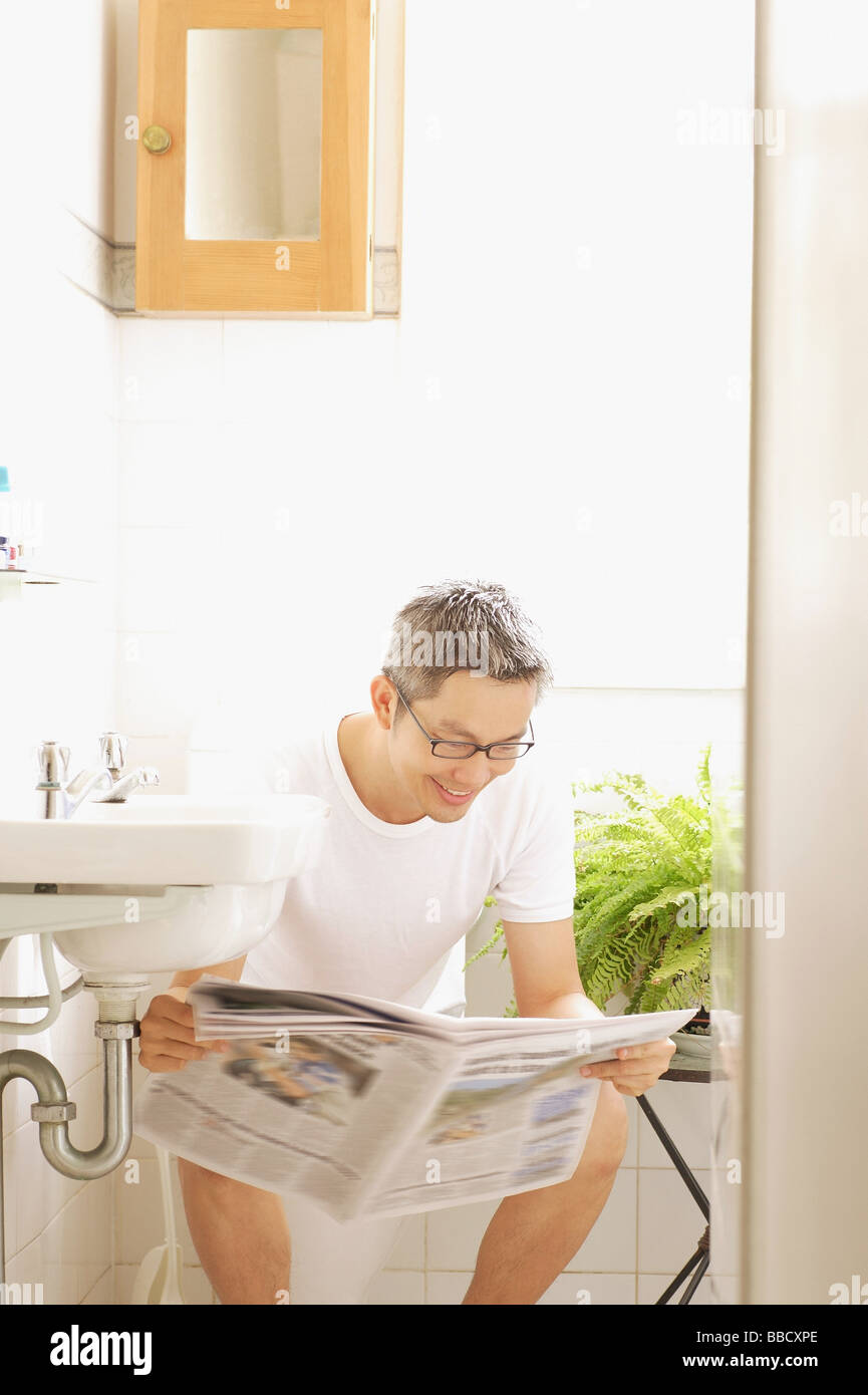 Man on toilet, reading newspaper Stock Photo - Alamy