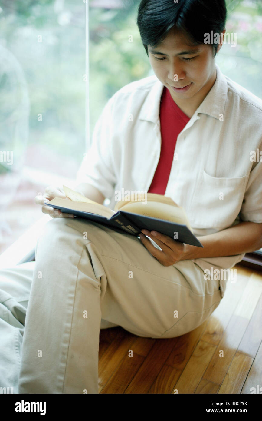 Man leaning on window, reading a book Stock Photo - Alamy