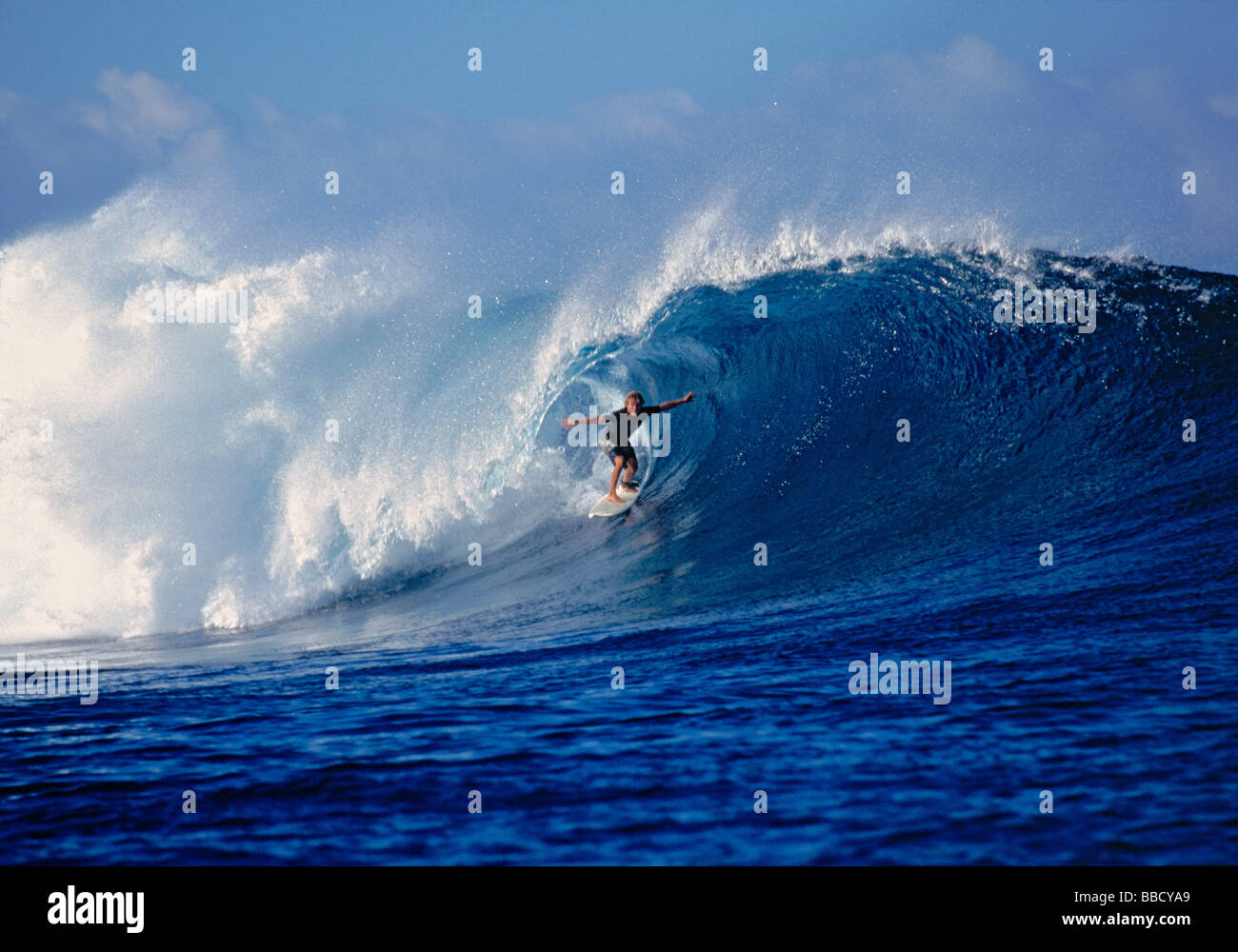 A surfer locks into the tube on a twenty foot wave at Cloudbreak ...