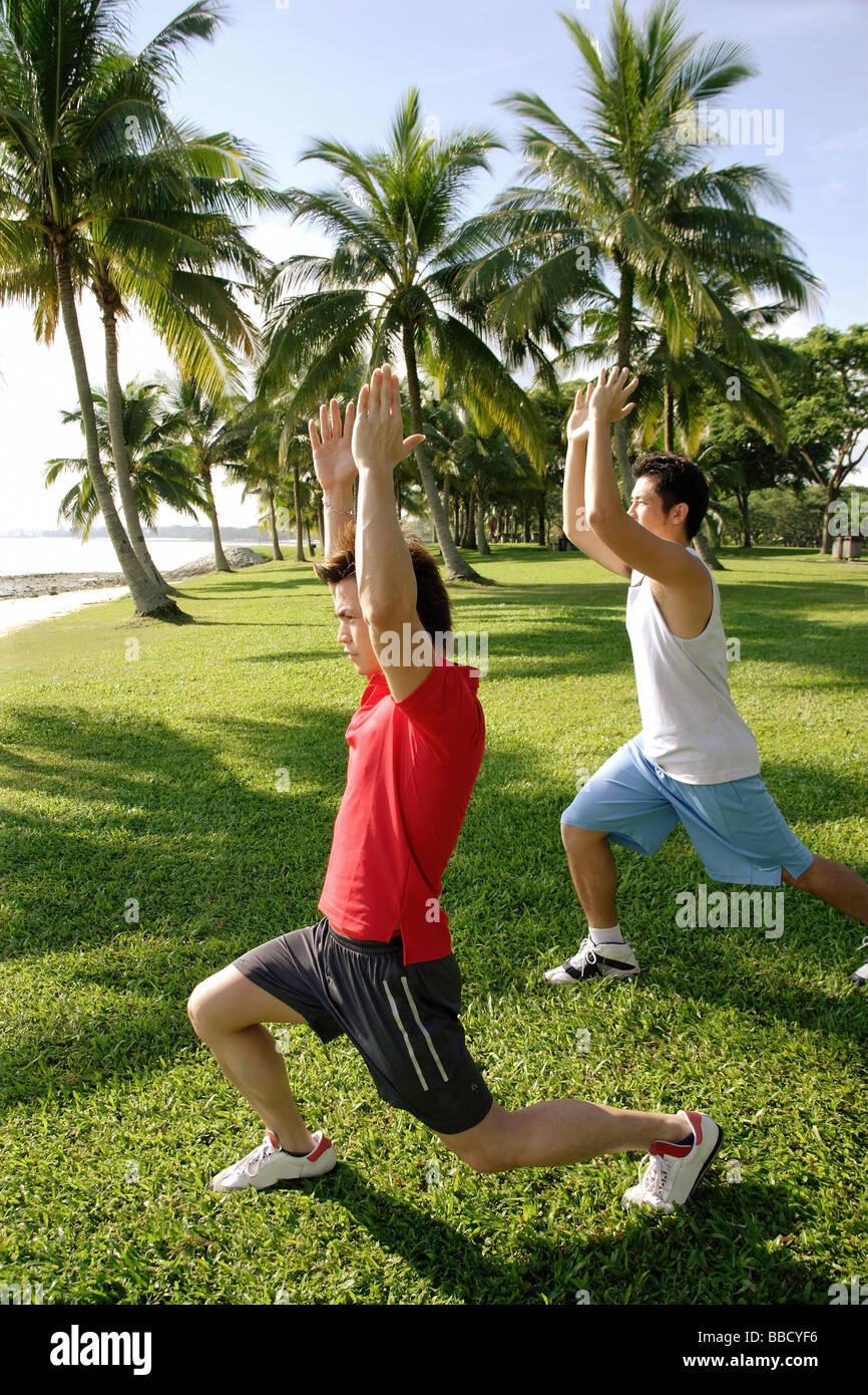 Men doing stretching exercises in park, arms raised upward Stock Photo ...