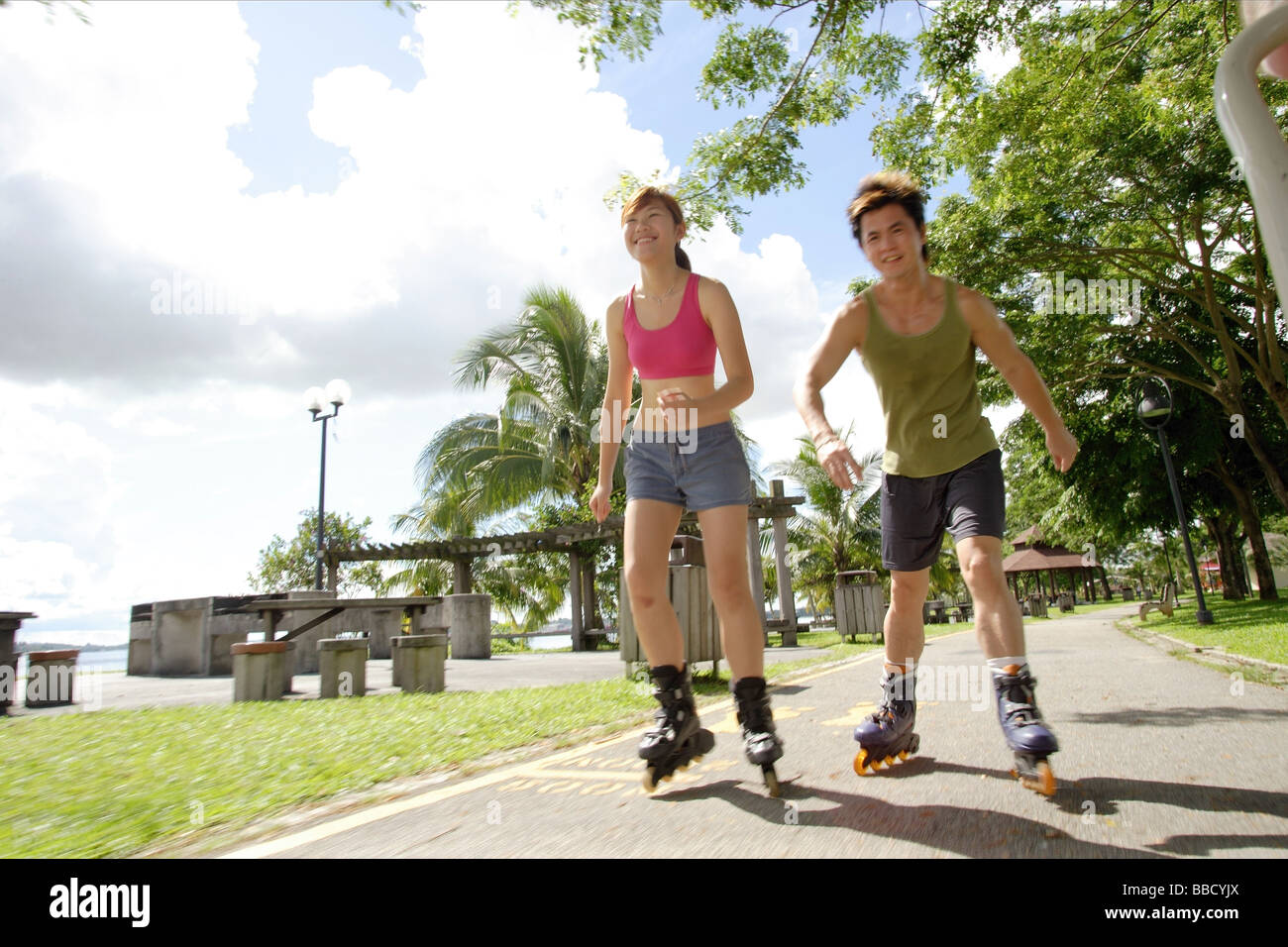 Couple inline skating at park, low angle view Stock Photo - Alamy