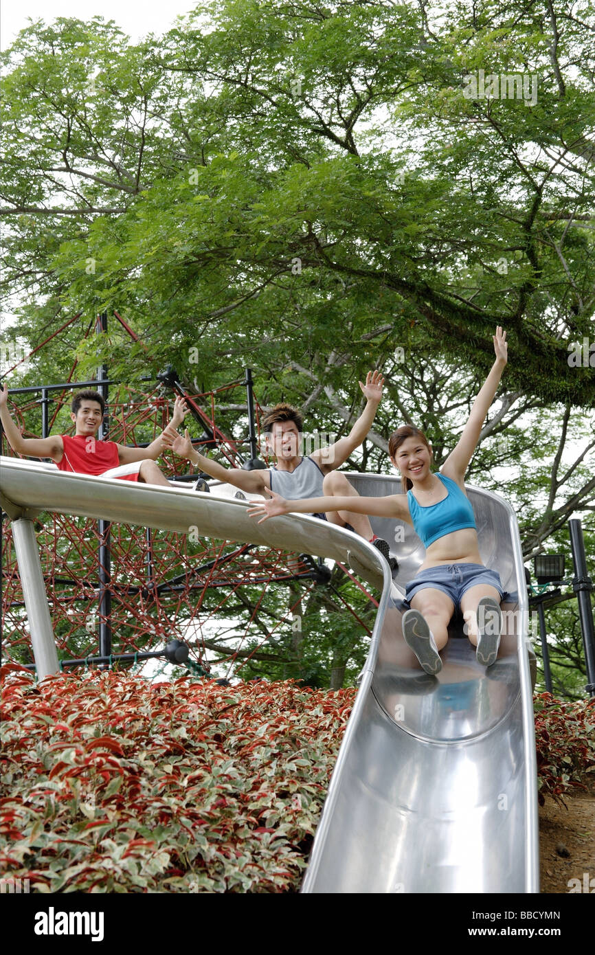 Group of young people sliding down playground slide Stock Photo - Alamy