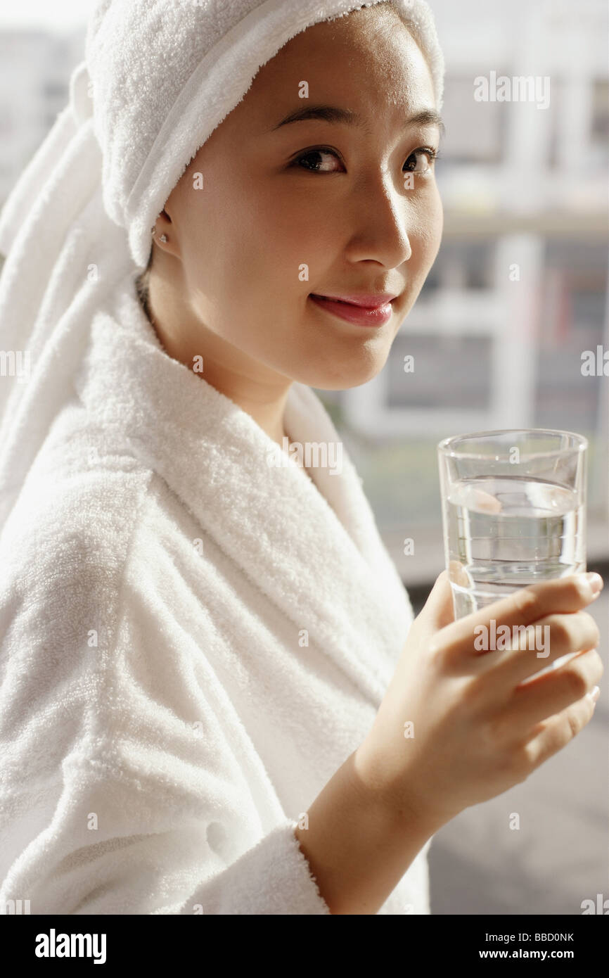 Young woman in robe holding glass of water Stock Photo - Alamy