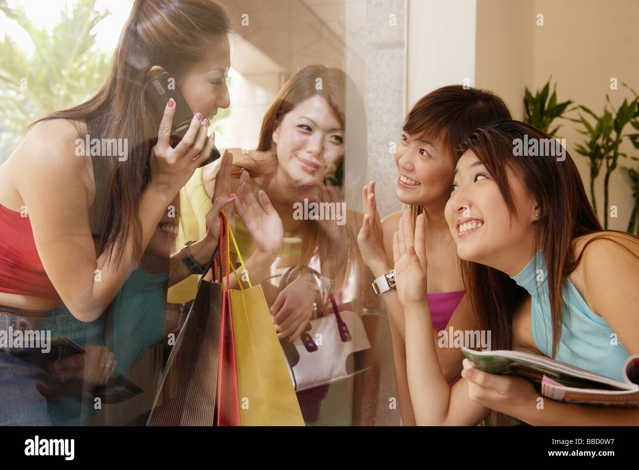 Young women waving at each other through glass window Stock Photo - Alamy