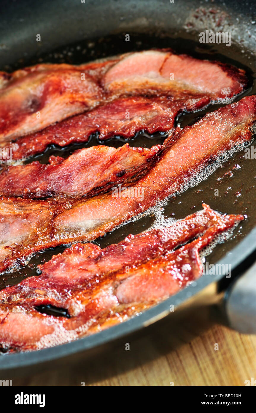 Bacon strips sizzling on a frying pan Stock Photo - Alamy