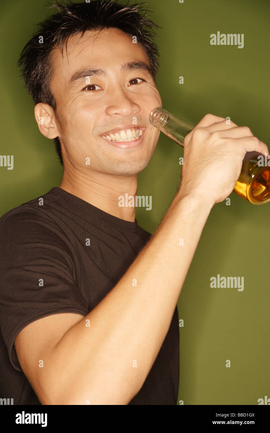 Young man raising beer bottle Stock Photo - Alamy
