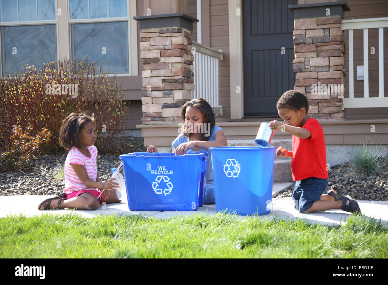 Three children putting items into recycle bin Stock Photo - Alamy