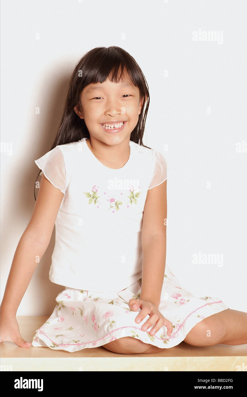 Girl sitting down, looking at camera, smiling Stock Photo - Alamy