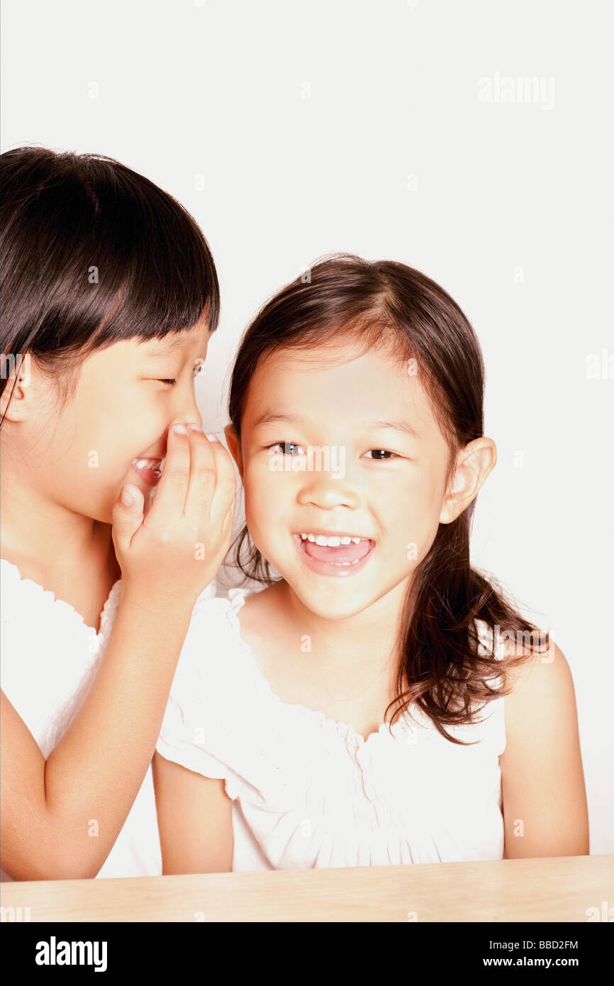Girl whispering in young girl's ear Stock Photo - Alamy