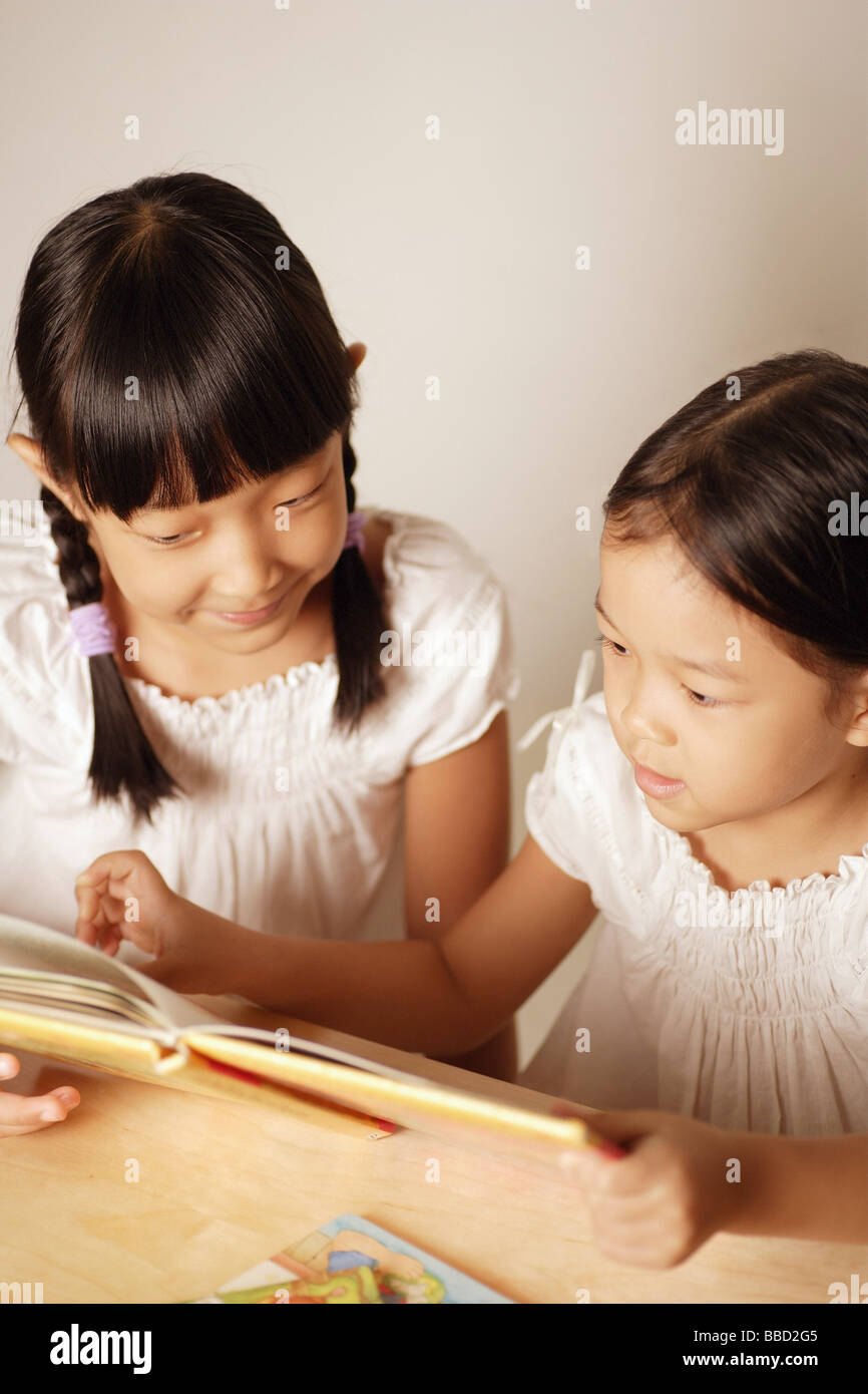 Two girls reading a book Stock Photo - Alamy
