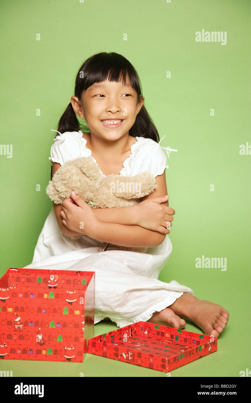 Girl hugging stuffed toy, wrapped box open in front of her Stock Photo ...