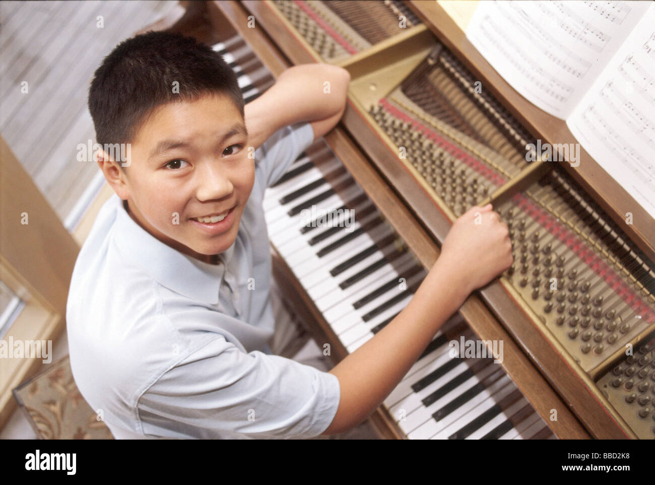 Boy sitting at piano, looking up at camera Stock Photo - Alamy