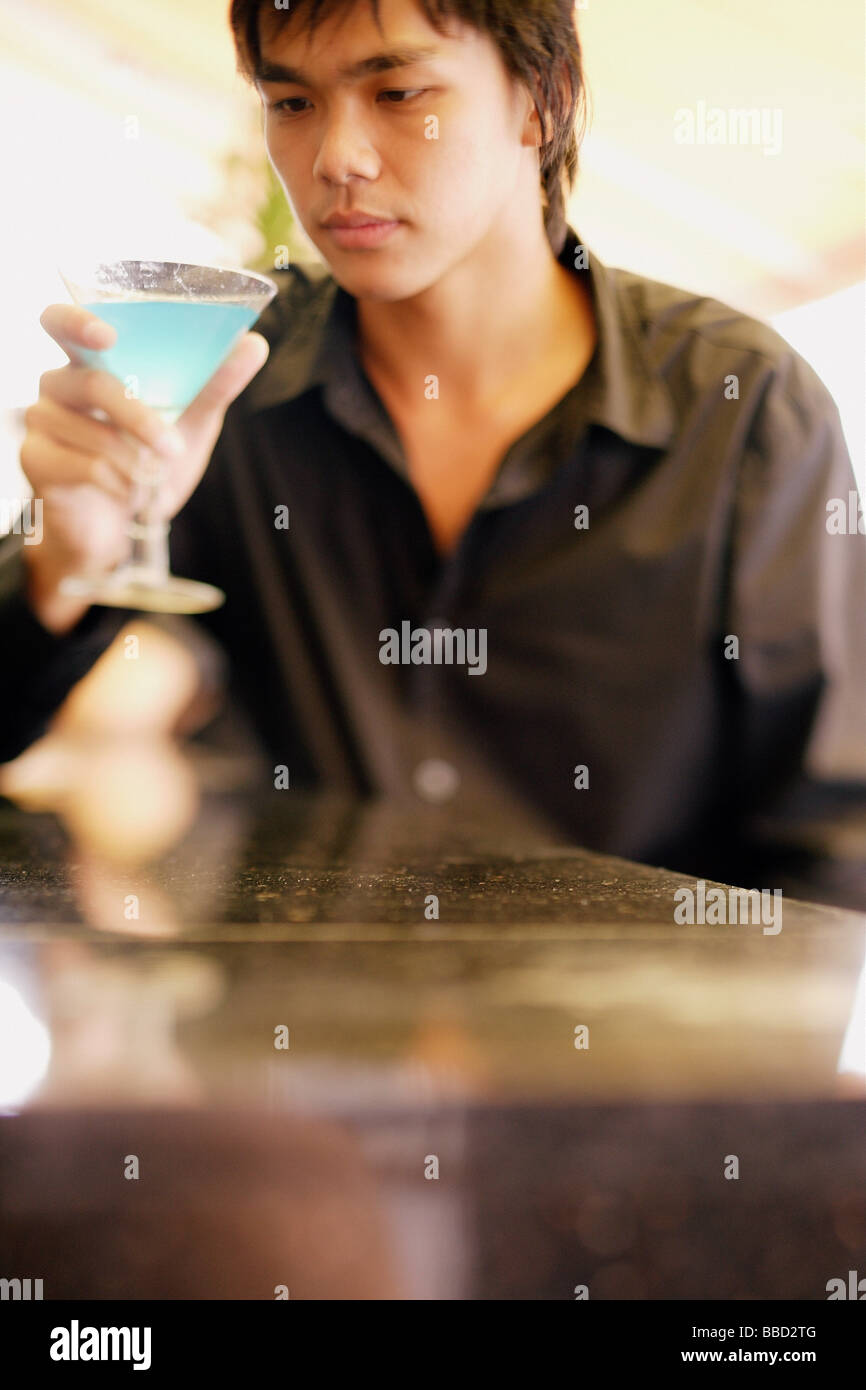 Young man at bar counter holding and looking at cocktail glass Stock ...