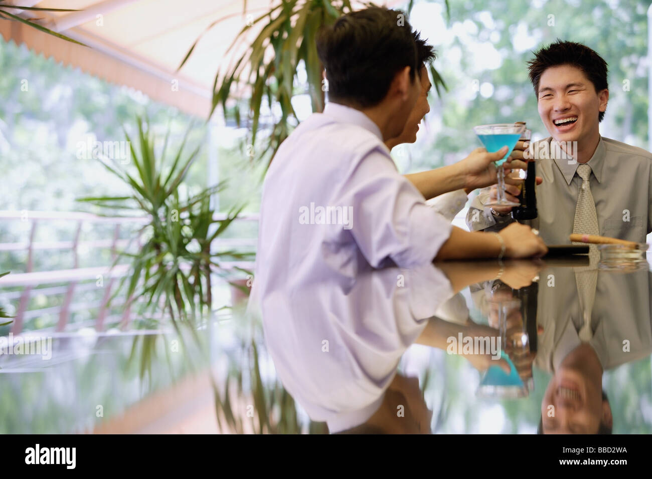 Young men at bar counter, raising drinks for a toast Stock Photo - Alamy