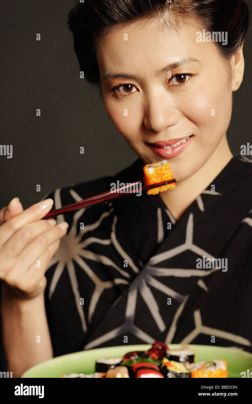 Woman in Japanese costume, eating sushi, portrait Stock Photo - Alamy