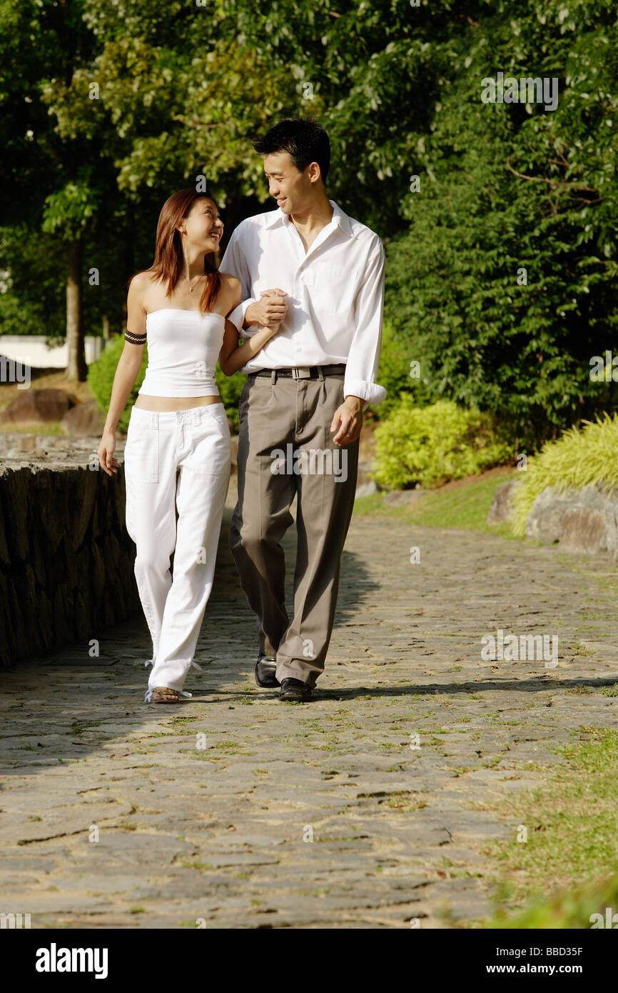Couple walking through park, side by side, holding hands Stock Photo ...