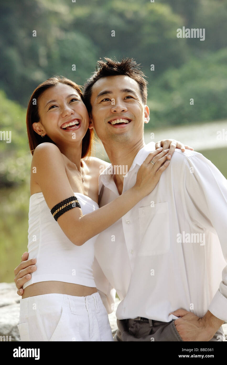 Couple hugging, looking up, smiling Stock Photo - Alamy