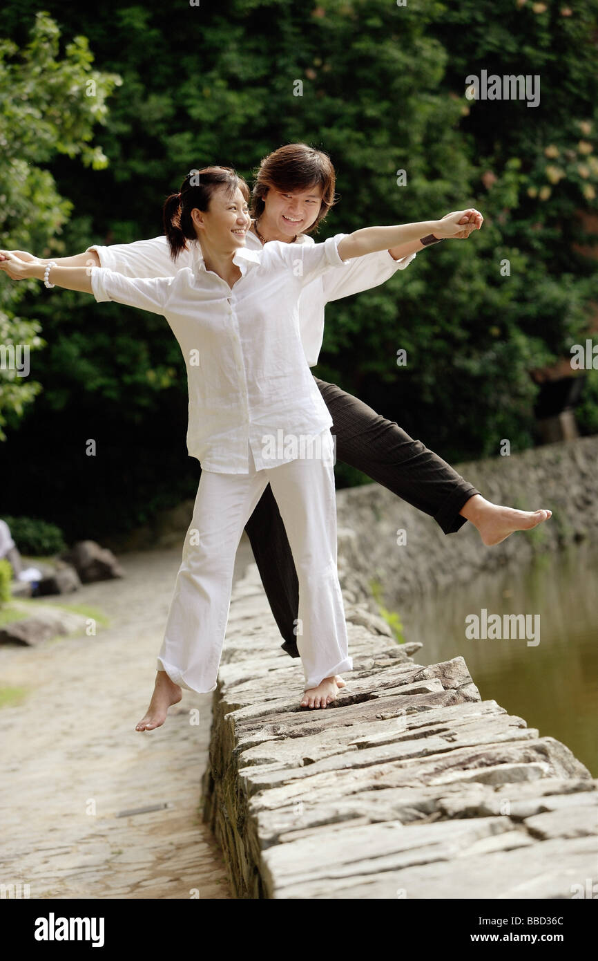 Couple balancing along ledge, arms outstretched Stock Photo - Alamy