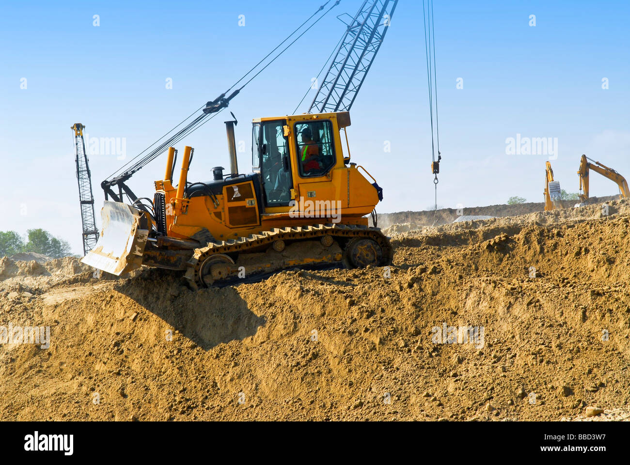Yellow bulldozer machines digging and moving earth at construction site ...
