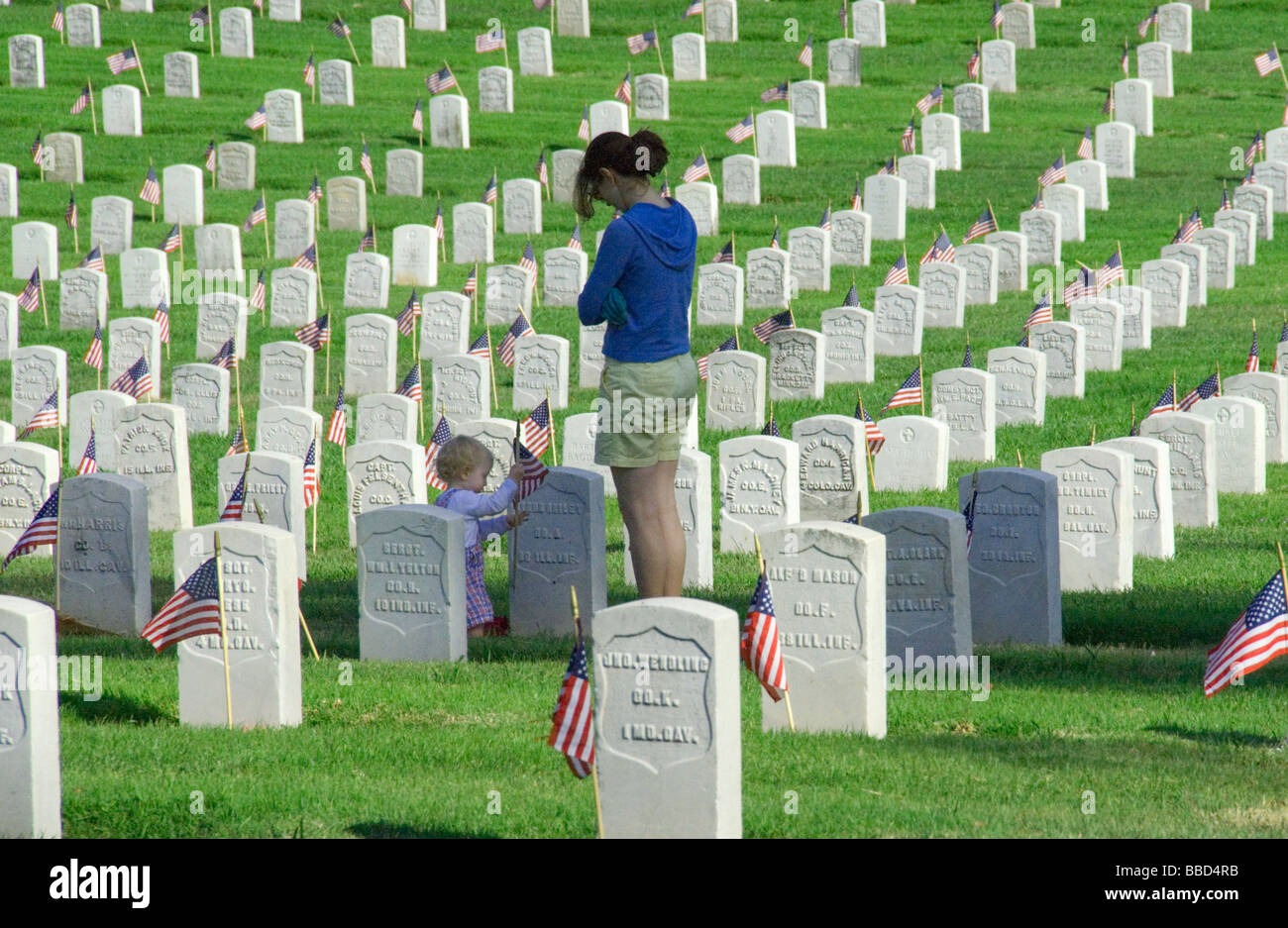 A widow and her small child put a flag on the tomb of the husband and ...