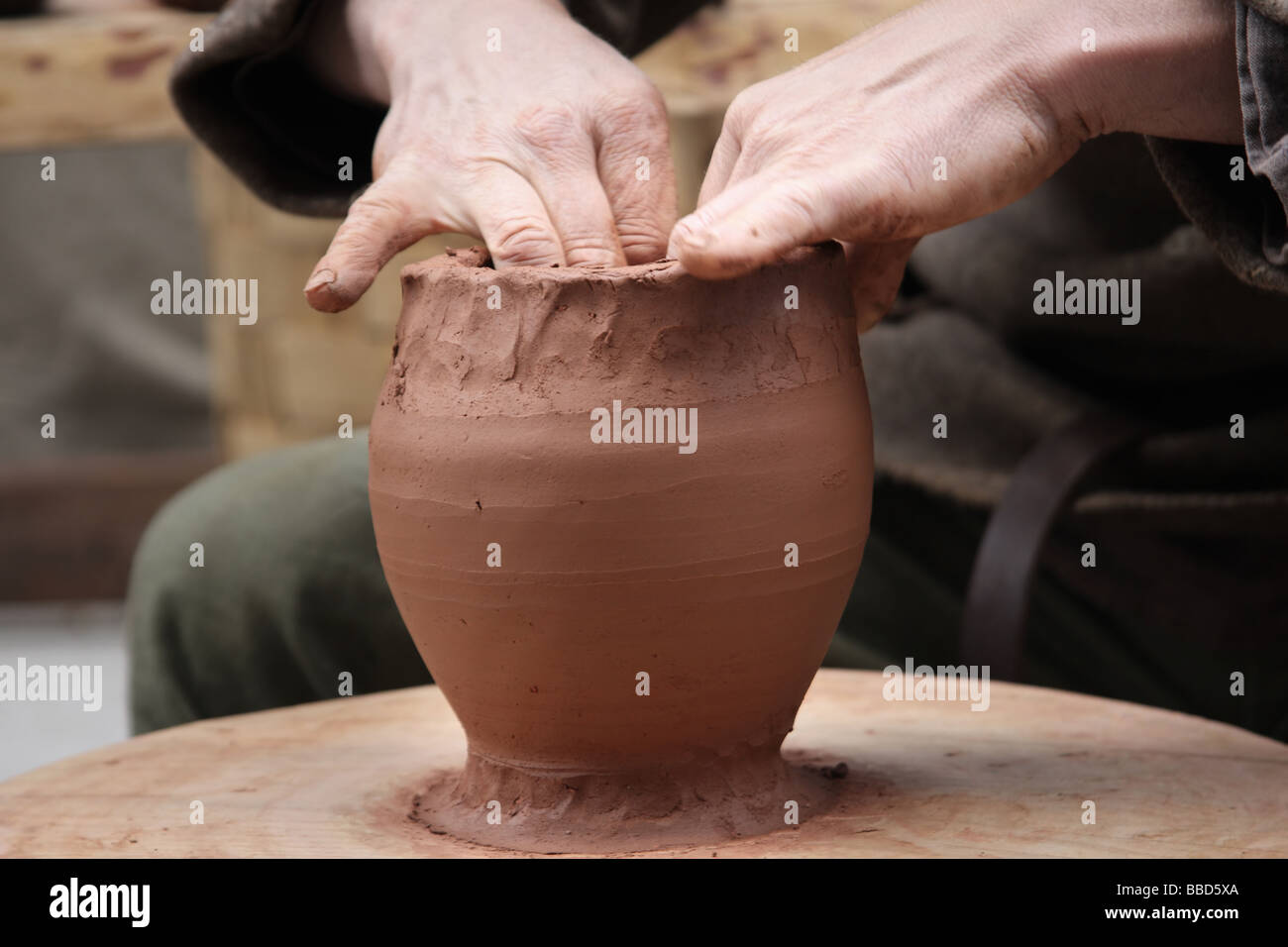 An artist making a clay pot in the traditional method on a potters ...