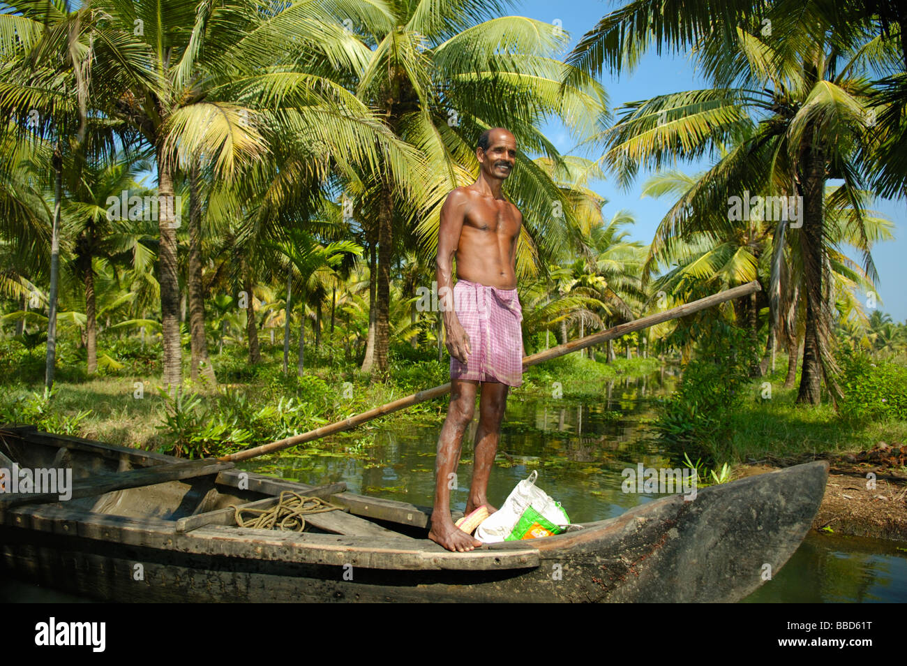 India, Kerala, backwaters. Indian boatman with a punt pole on a boat in ...
