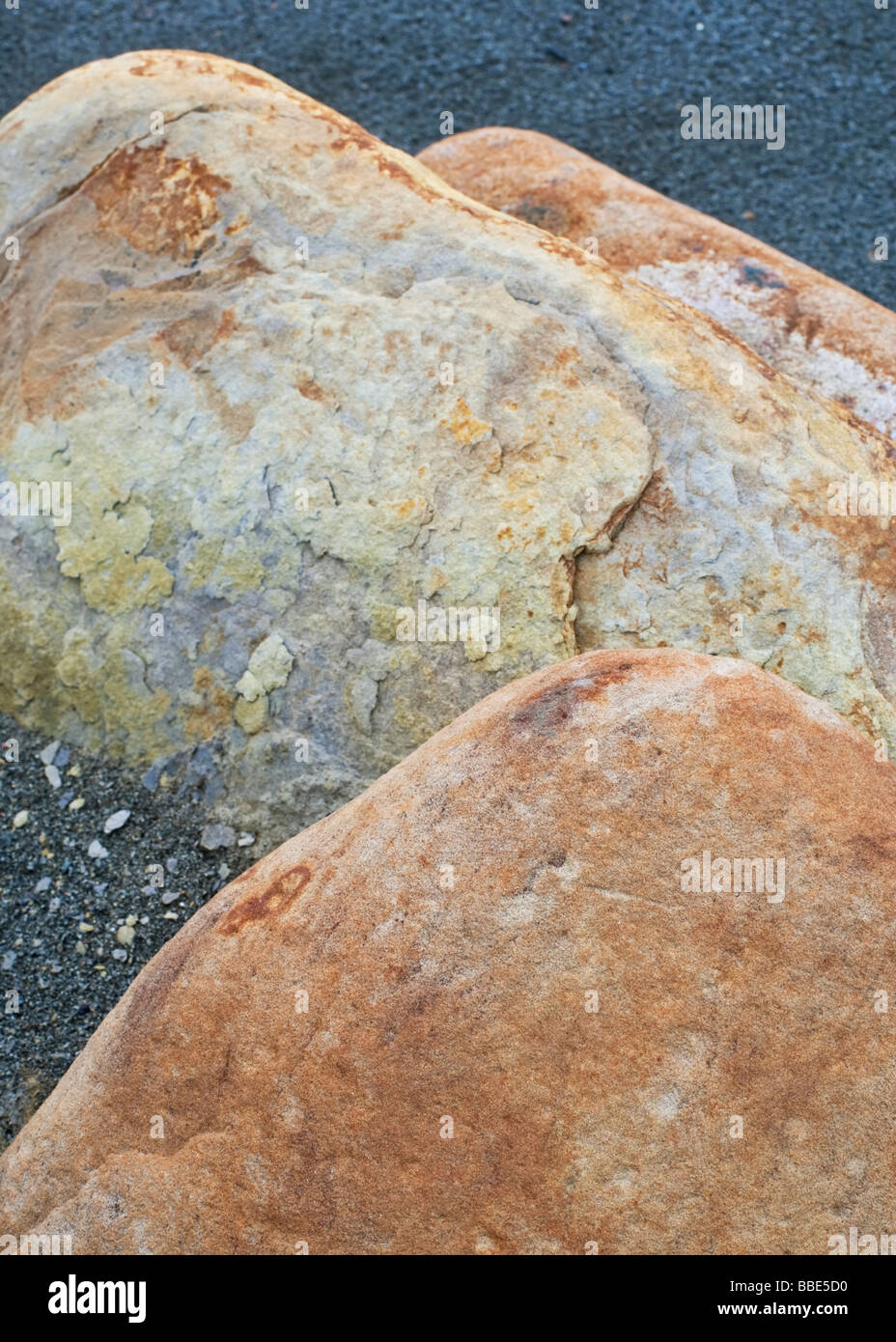 Sandstone boulders emerging from the black sand of Blast Beach near the ...
