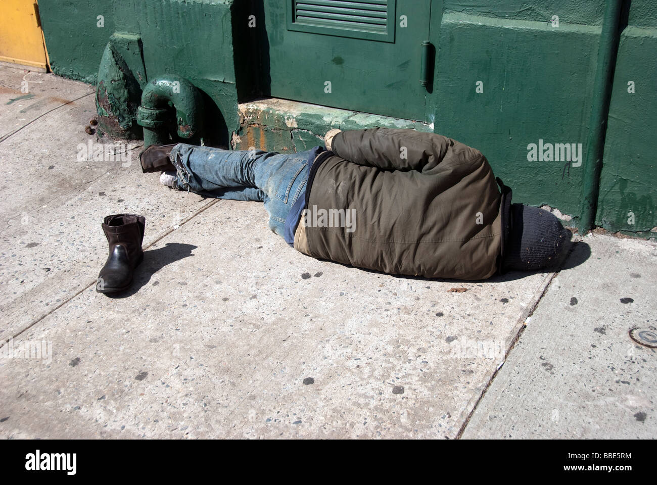 homeless man with stray boot asleep on the sidewalk in the Hells ...