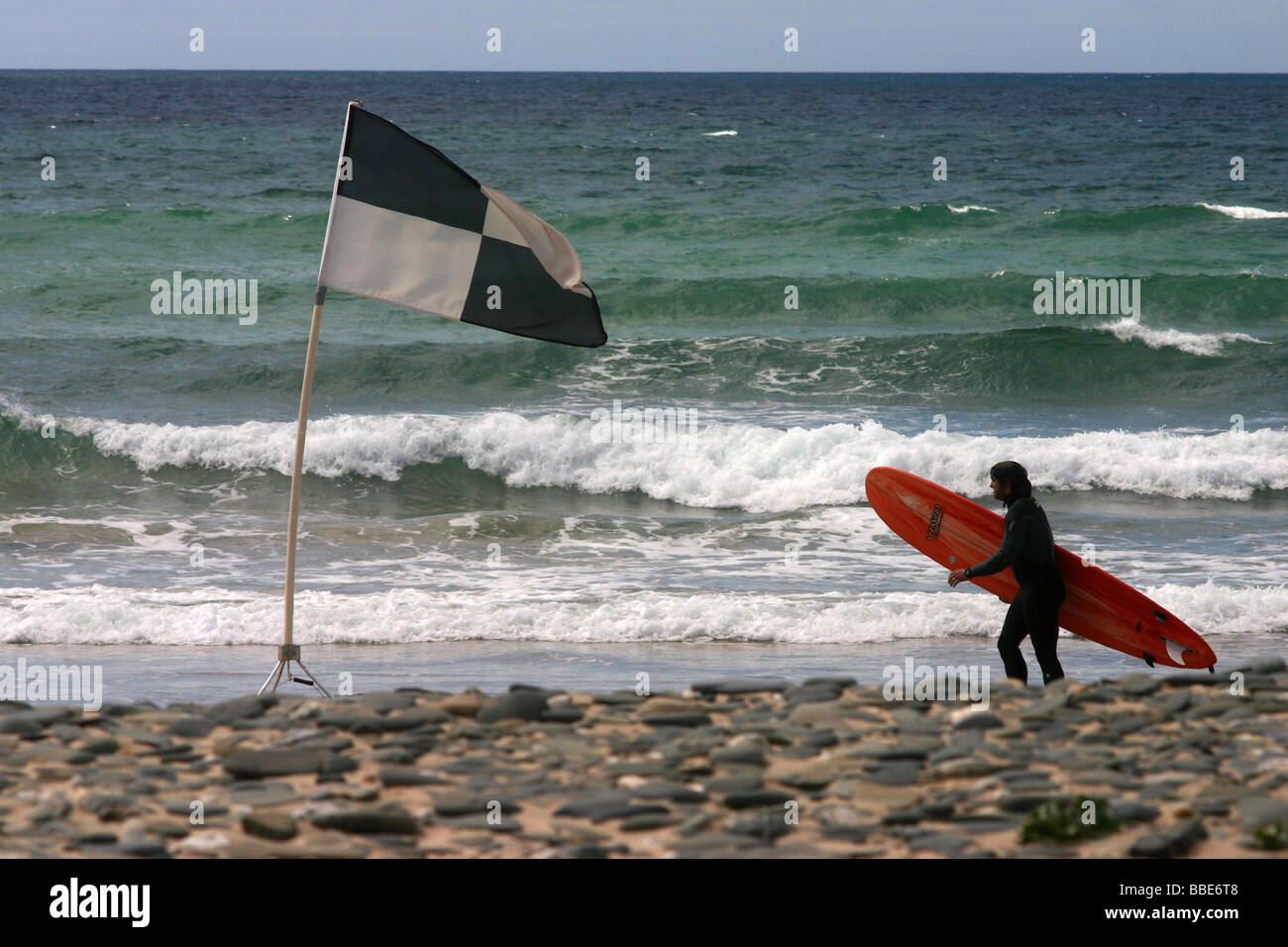 Surfer with safety flag flying on beach West Cornwall UK Stock Photo ...
