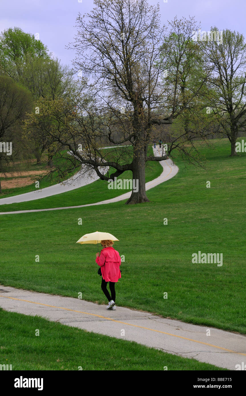 A woman carrying an umbrella walks the paved path in Valley Forge ...