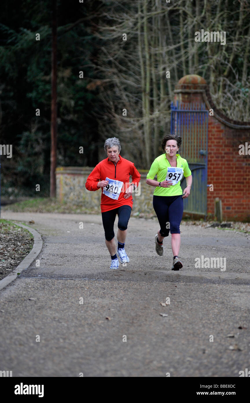 two women running side by side down park drive through wrought iron ...
