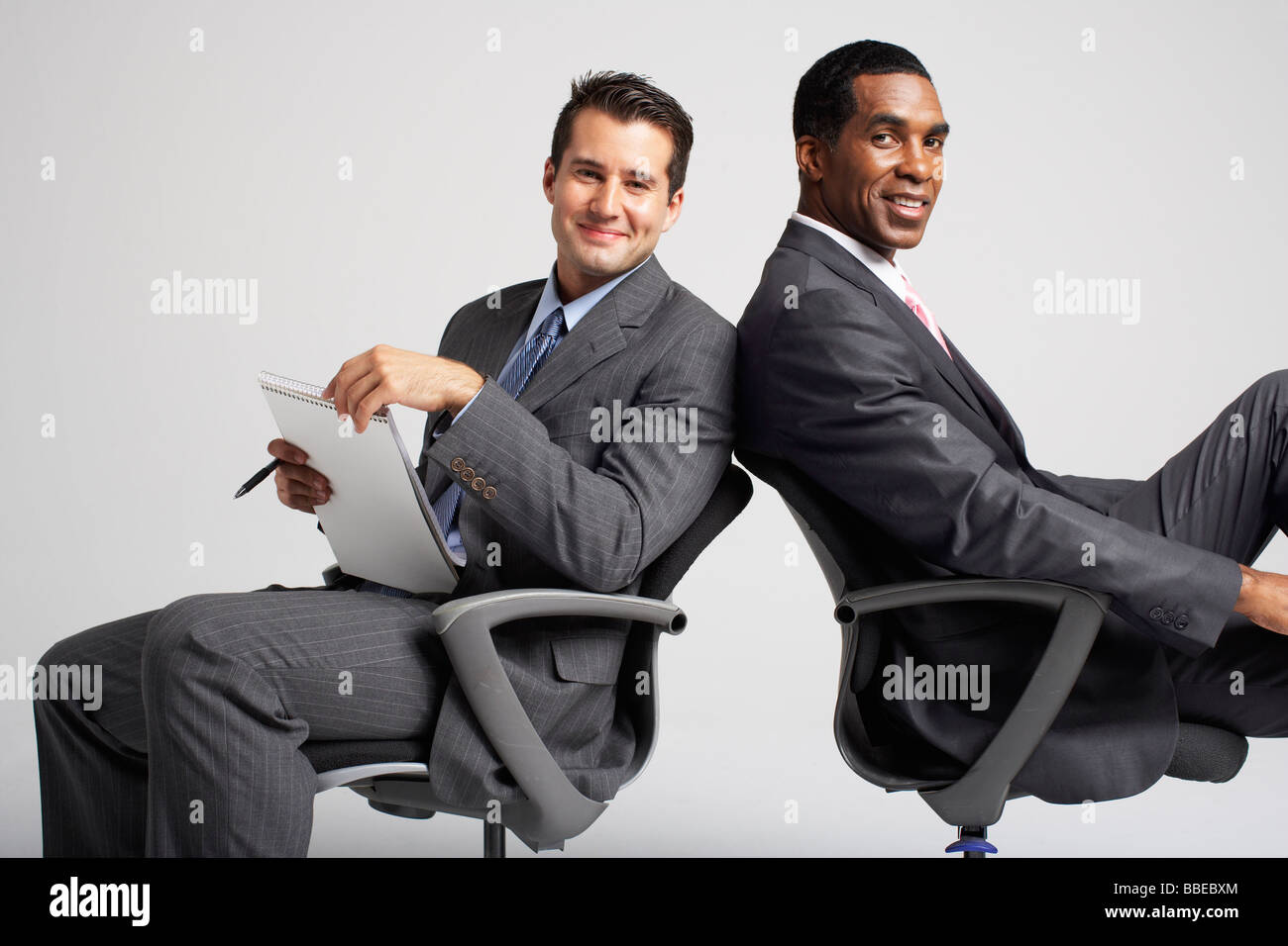 Businessmen Sitting Back to Back in Office Chairs Stock Photo - Alamy