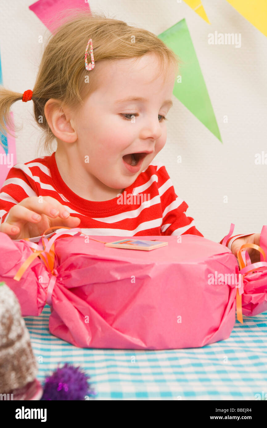 Little Girl Opening Gift at a Birthday Party Stock Photo - Alamy