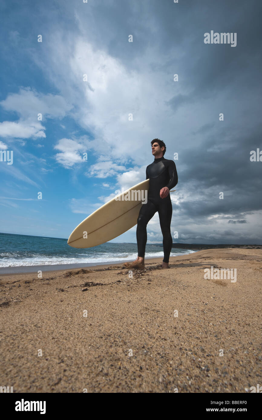 Surfer walking along the beach with his surfboard Stock Photo - Alamy