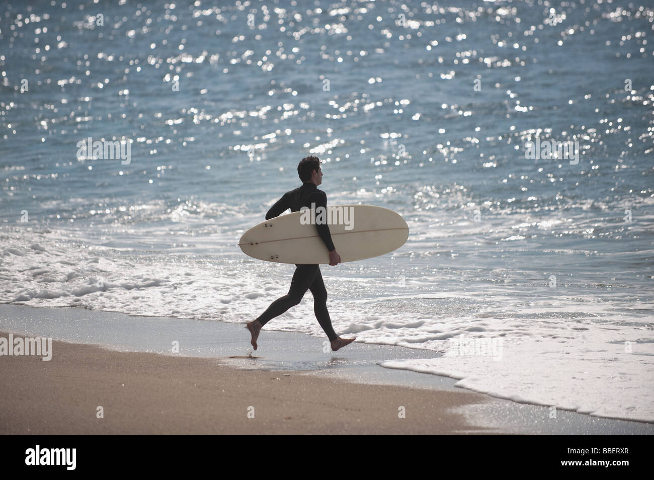Young man running toward sea with his surfboard Stock Photo - Alamy