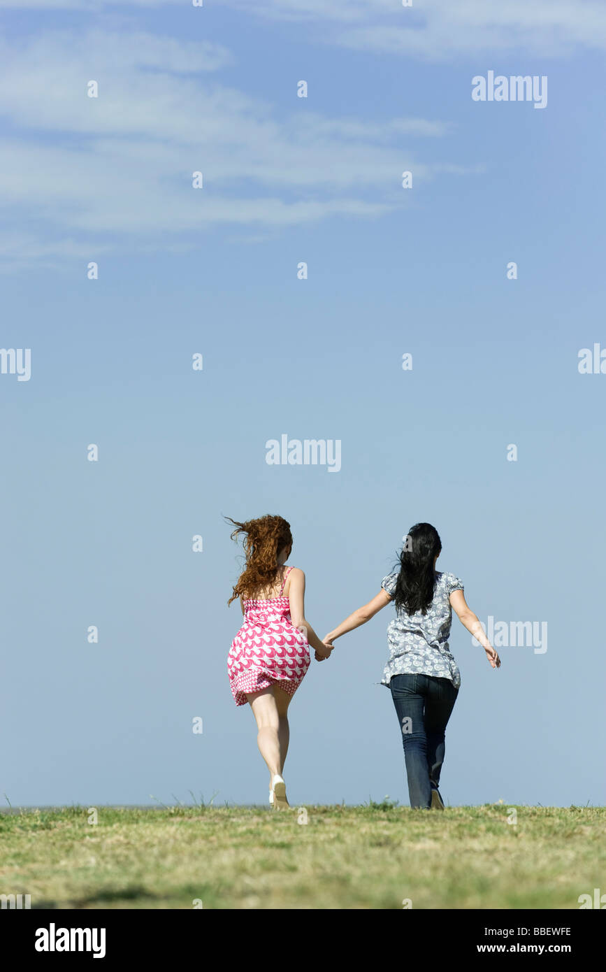 Two young women running hand in hand, rear view Stock Photo - Alamy