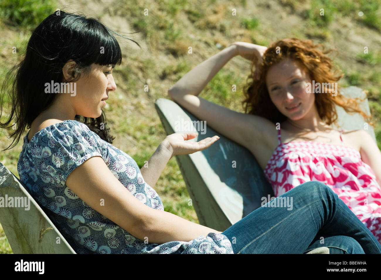 Two young women sitting outdoors, talking Stock Photo - Alamy