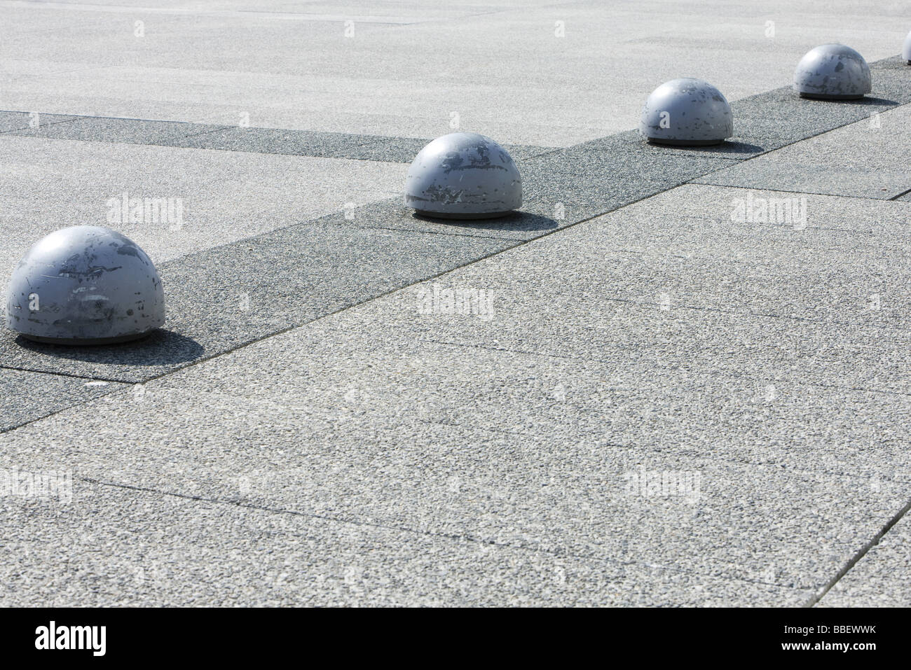 Bollards in line along aggregate concrete pavement Stock Photo - Alamy